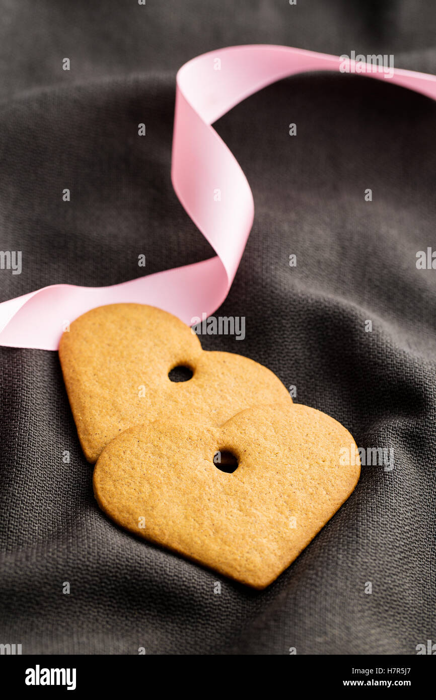 Two gingerbread hearts with pink ribbon on brown fabric Stock Photo - Alamy