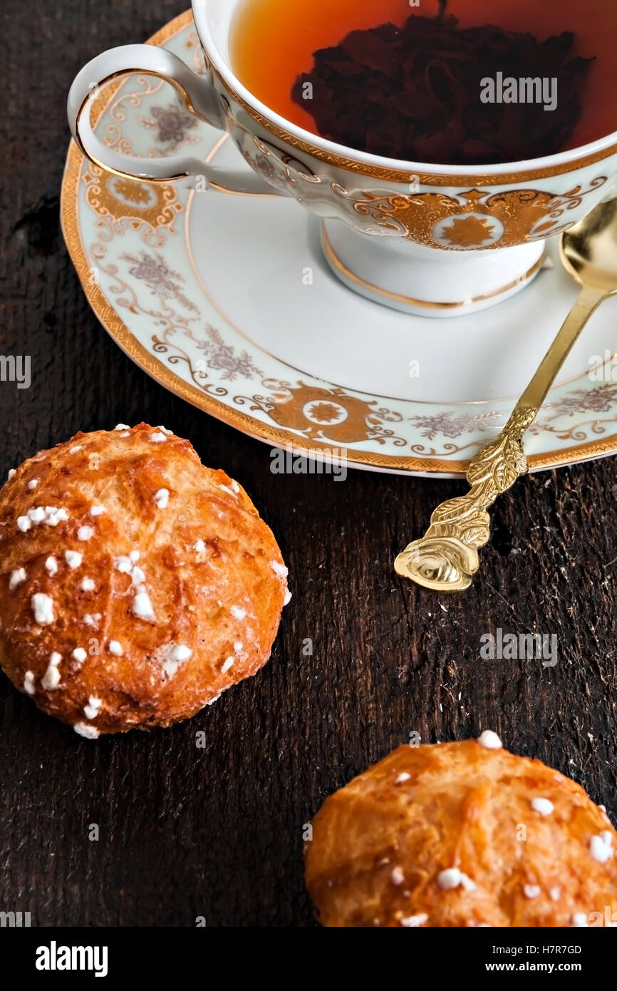profiteroles topped with sugar and vintage cup with tea on a dark ...