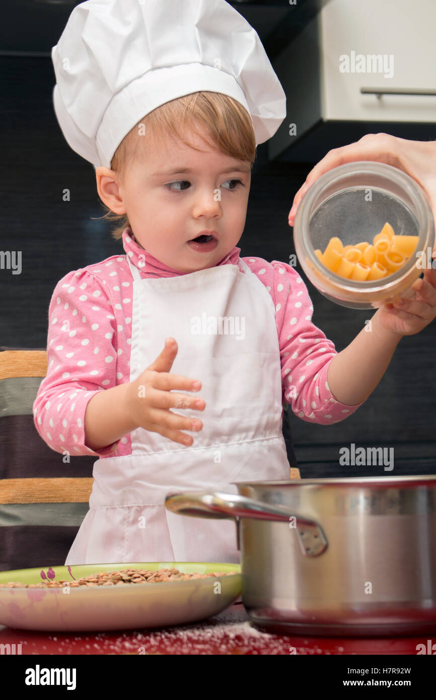 little cute child pours the pasta in a pan in the kitchen Stock Photo ...