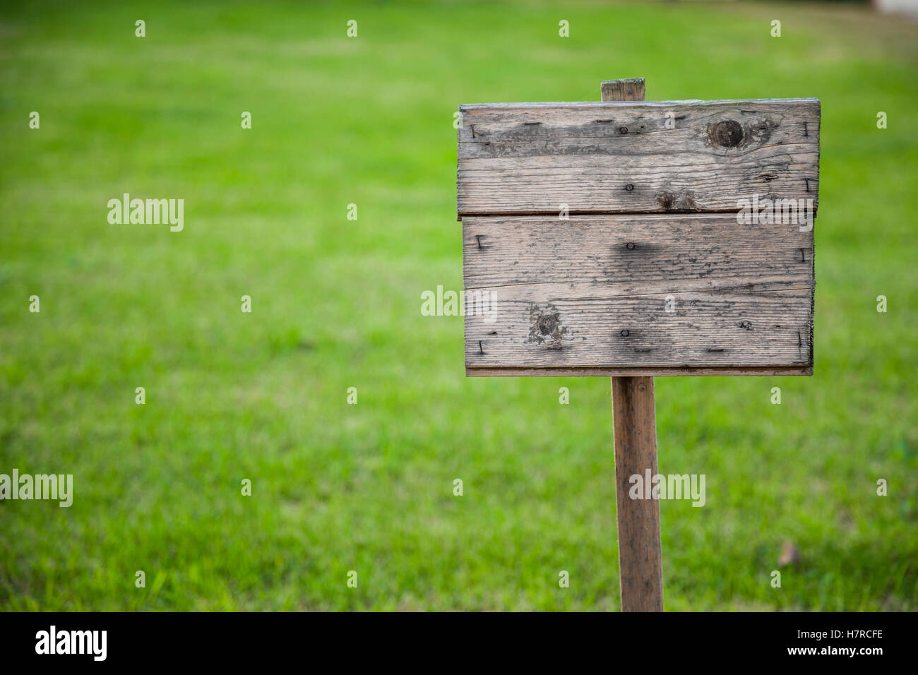 Wood weathered sign in front of grass Stock Photo - Alamy