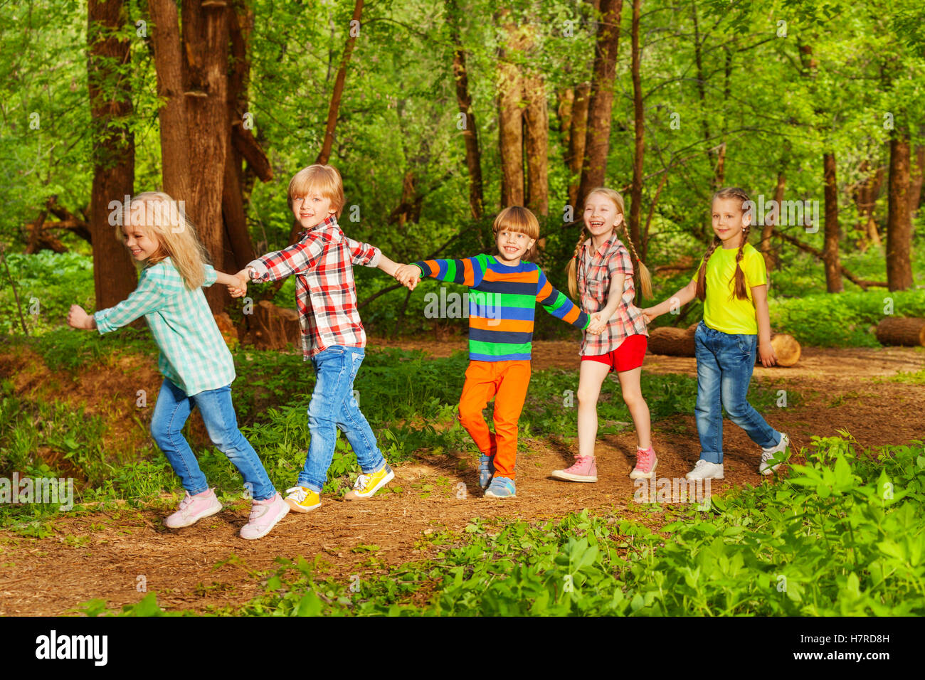 Five happy kids walking in forest holding hands Stock Photo - Alamy