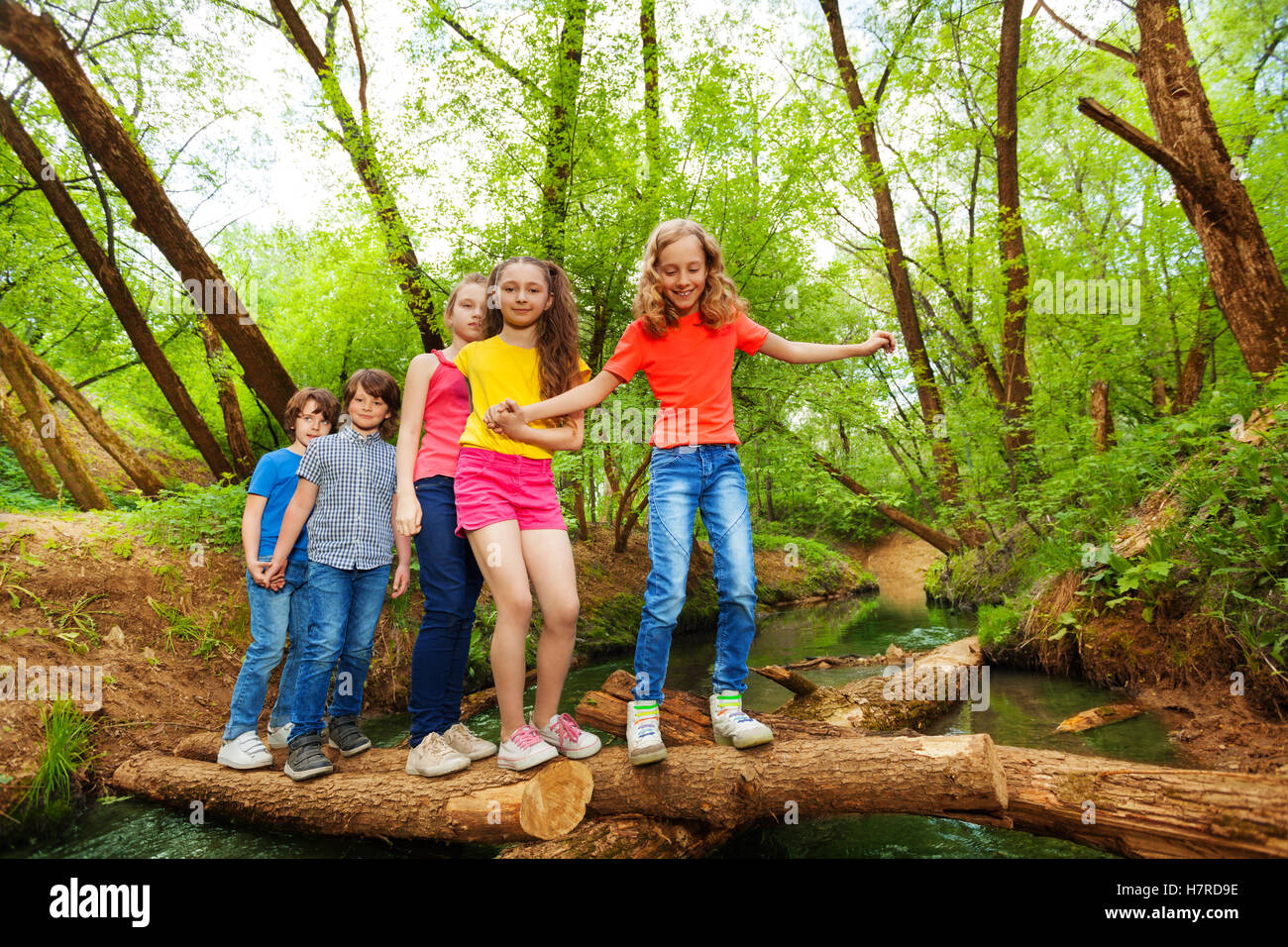Friends crossing through a log over the river Stock Photo - Alamy