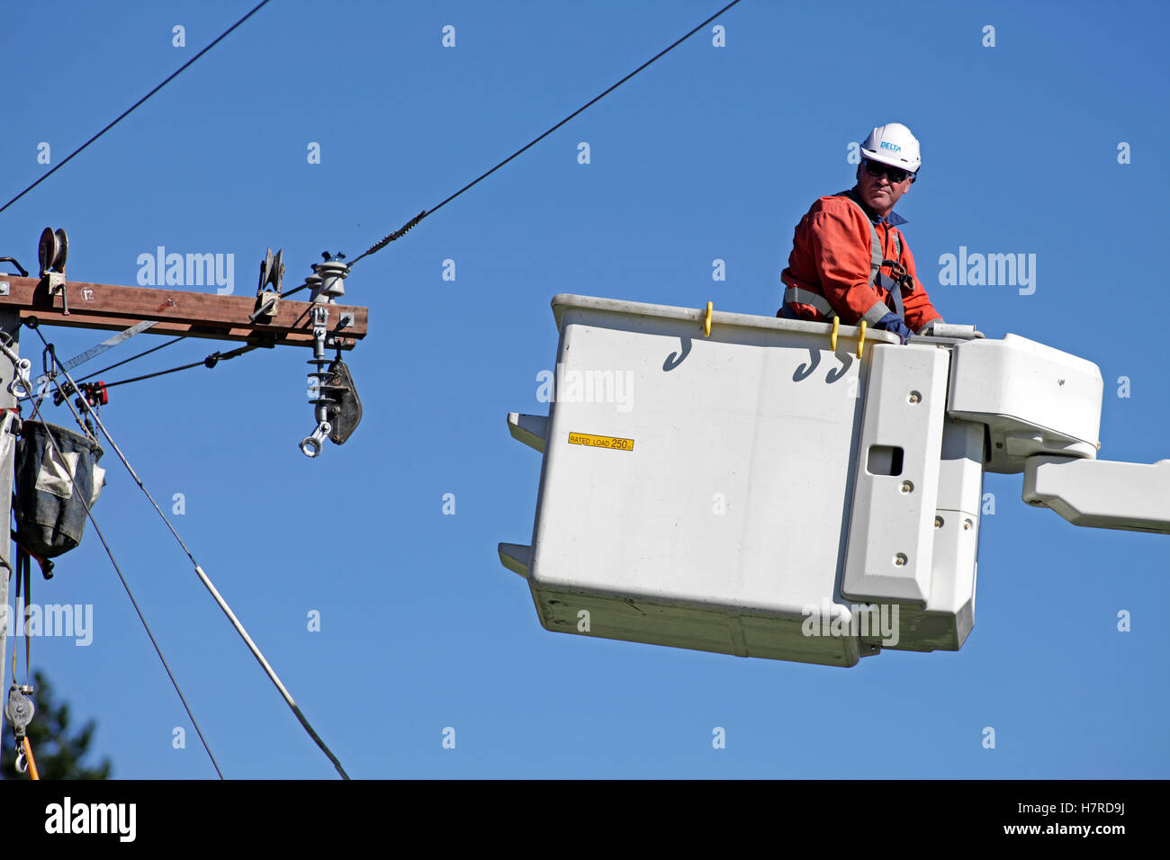 power company worker in a cherry picker hoist replacing high voltage ...