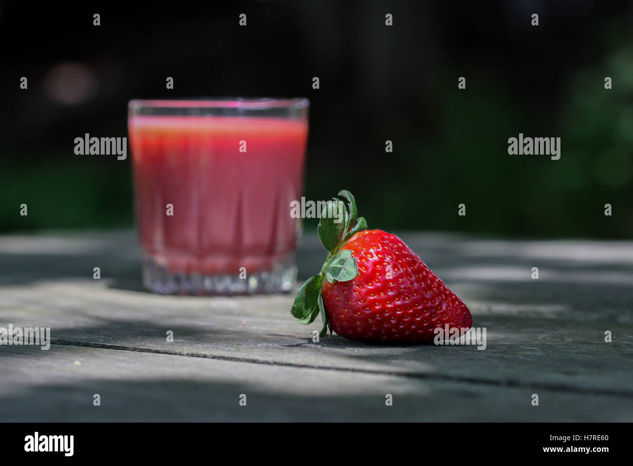One strawberry on wooden table with vitamin drink Stock Photo - Alamy