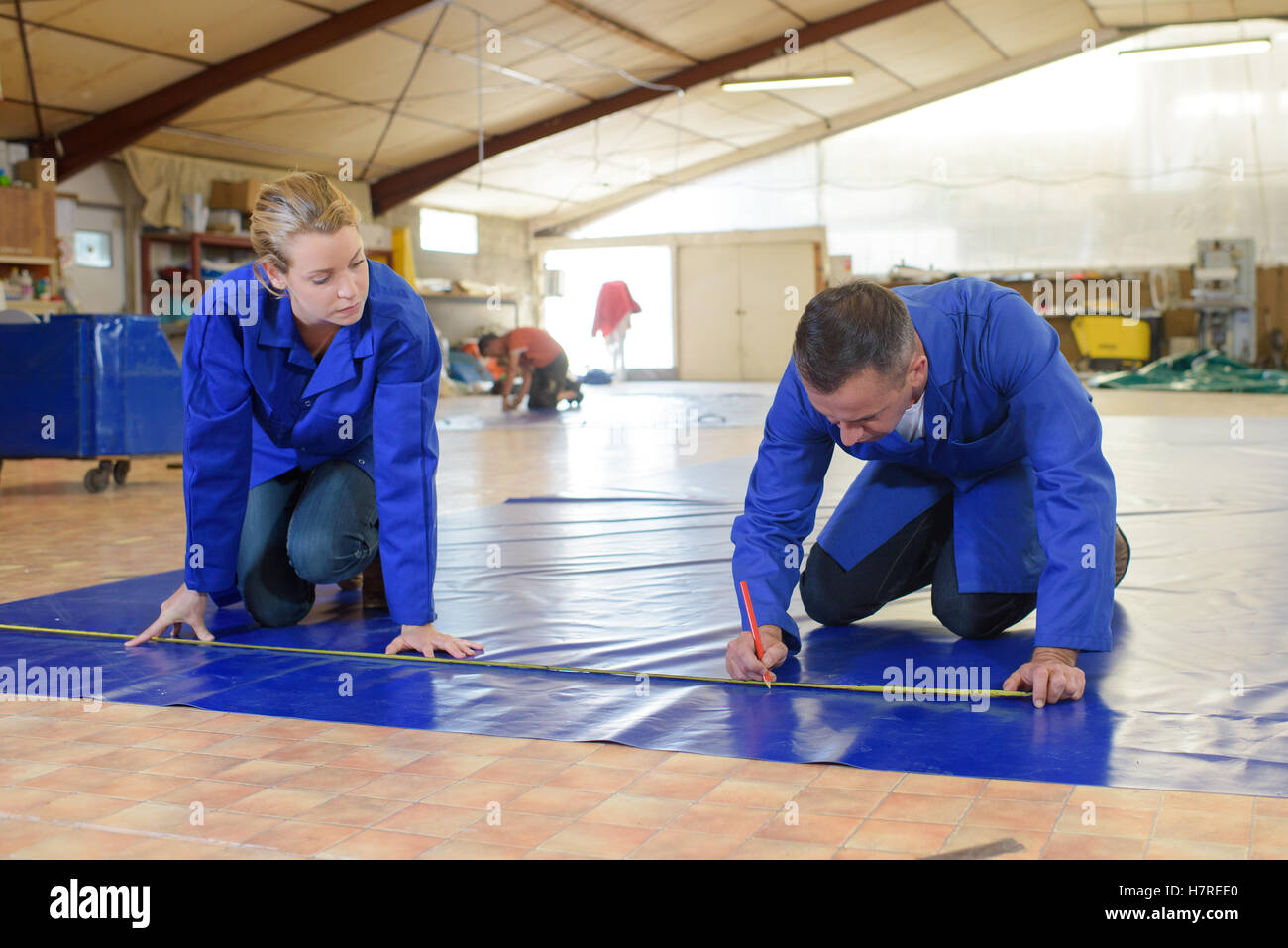 Two workers measuring material on floor Stock Photo - Alamy