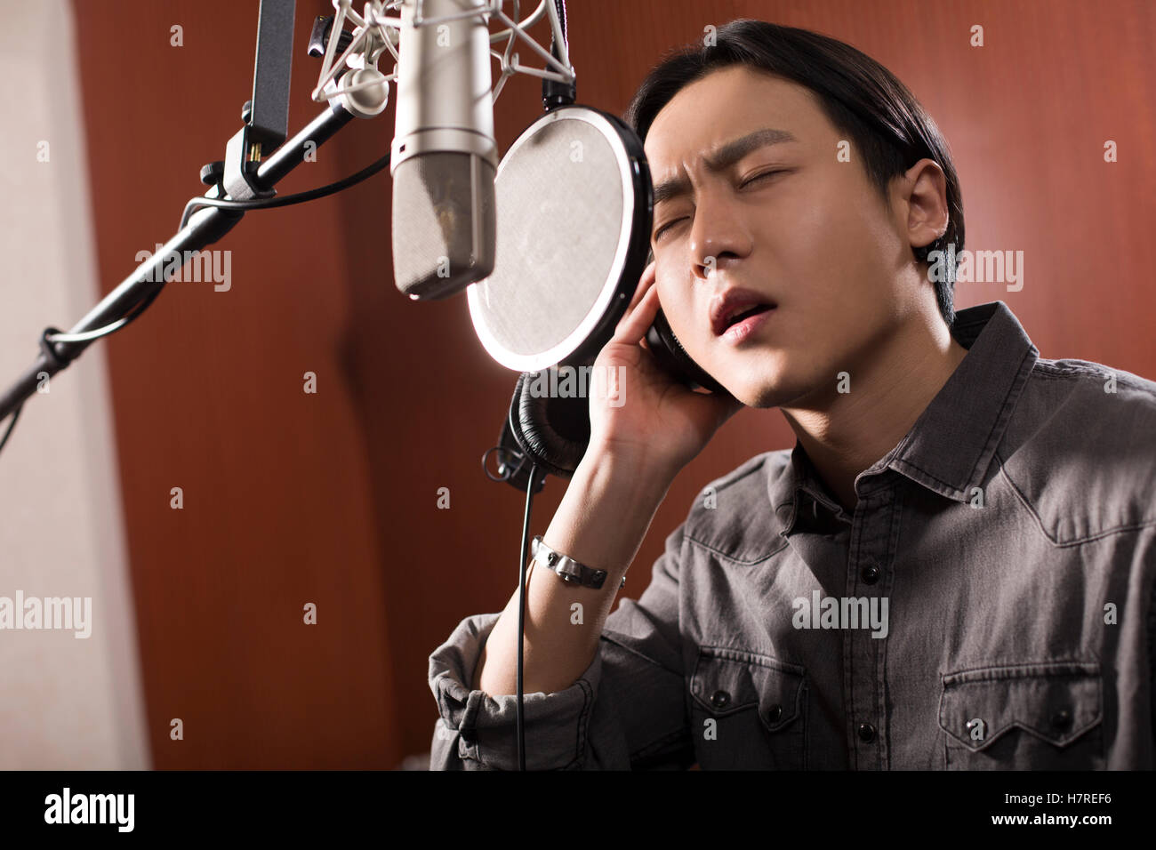 Young Chinese man singing in recording studio Stock Photo - Alamy