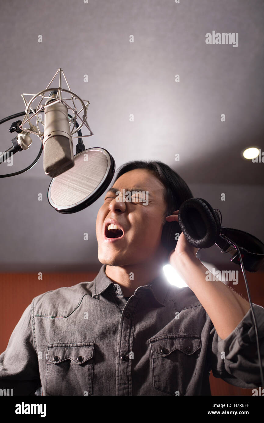 Young Chinese man singing in recording studio Stock Photo - Alamy