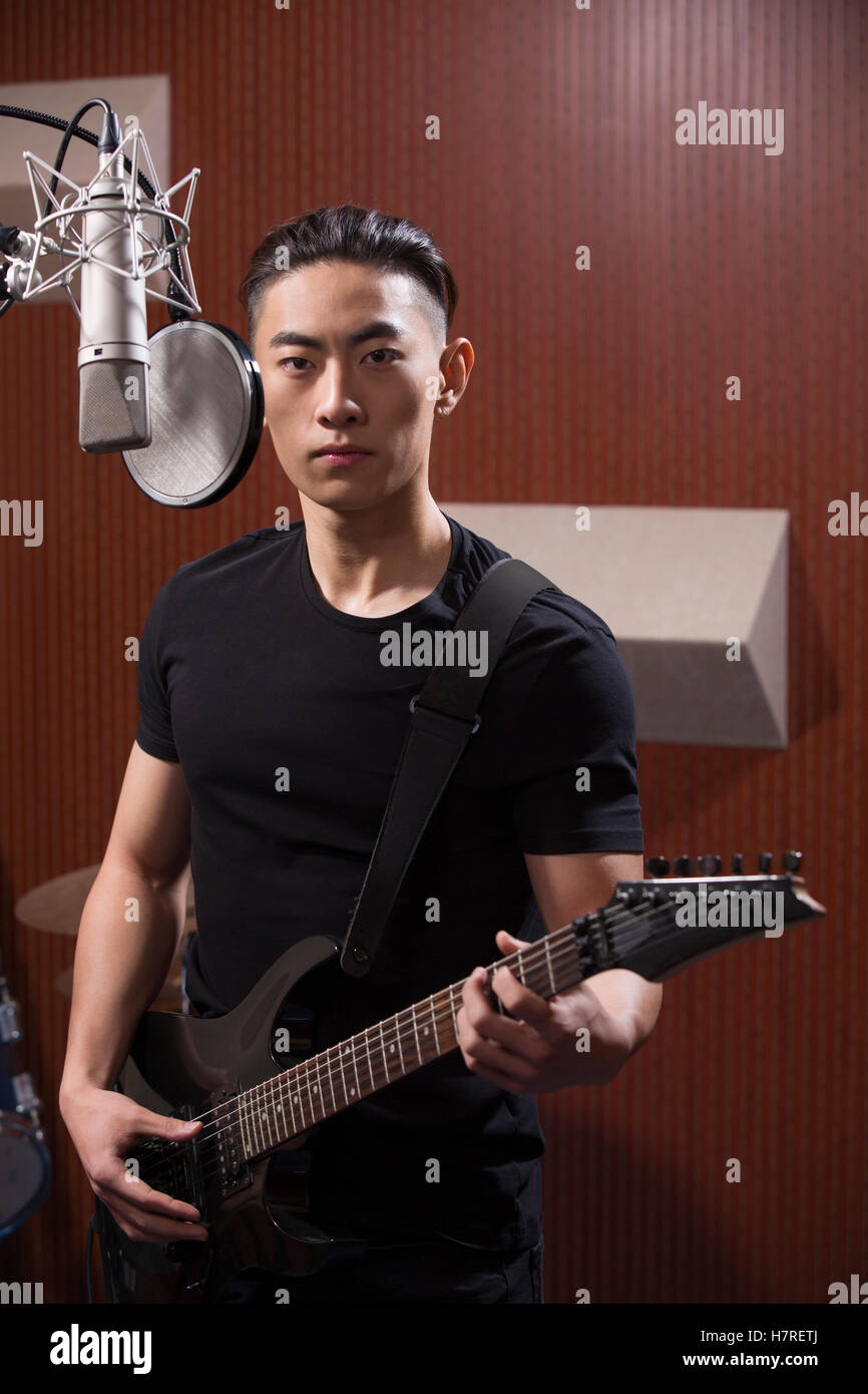 Young Chinese man singing with guitar in recording studio Stock Photo - Alamy