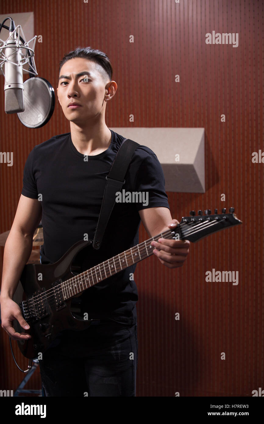 Young Chinese man singing with guitar in recording studio Stock Photo - Alamy
