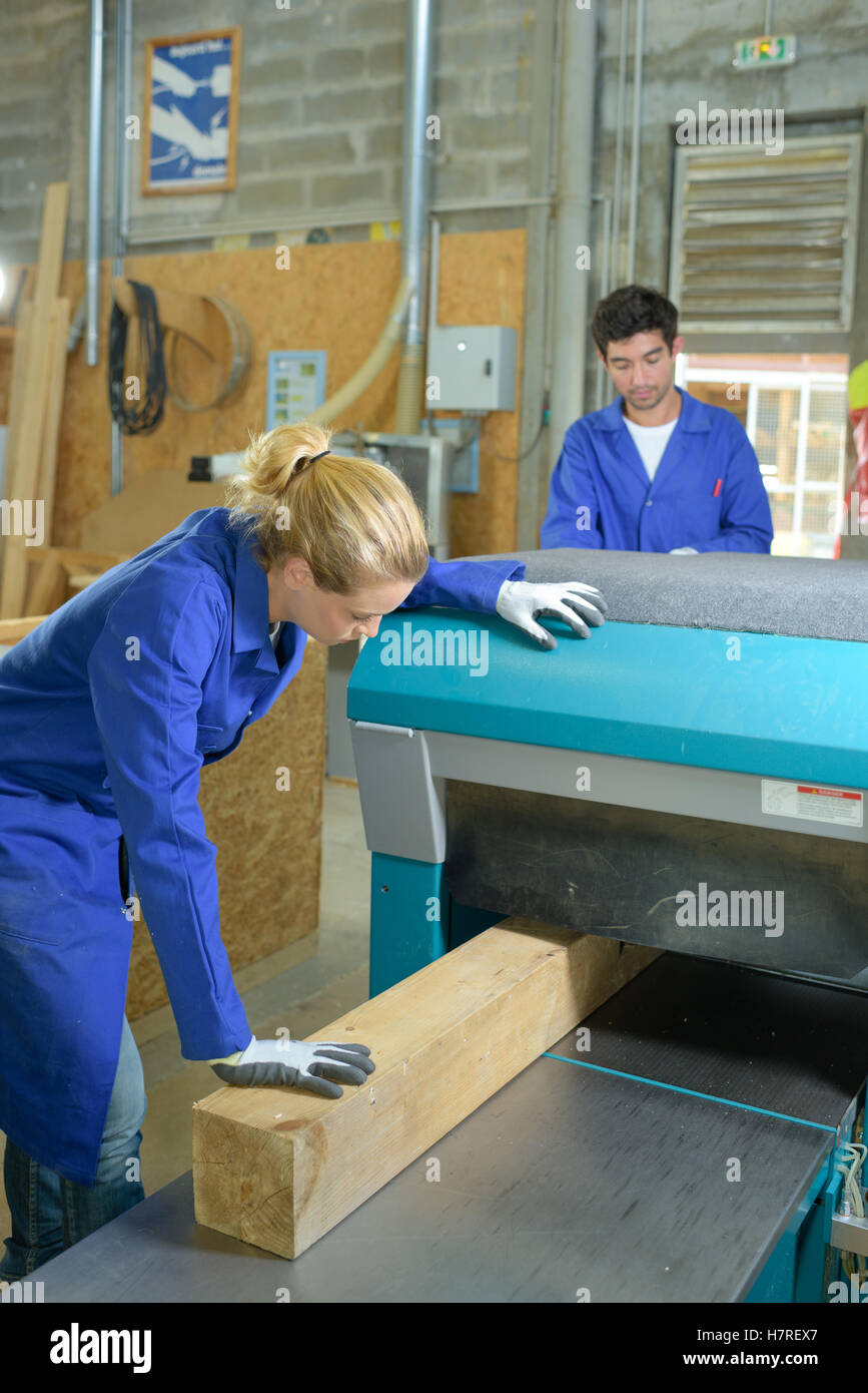 Woman pushing wood into machine Stock Photo - Alamy