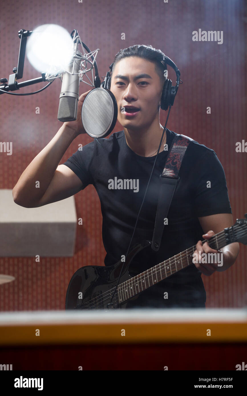 Young Chinese man singing with guitar in recording studio Stock Photo - Alamy