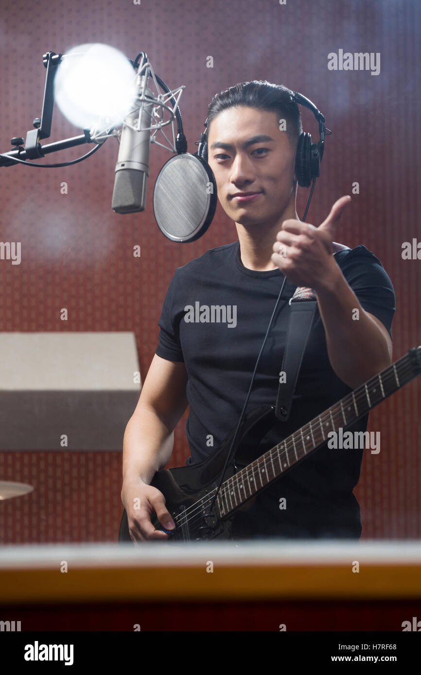 Young Chinese man singing with guitar in recording studio Stock Photo - Alamy