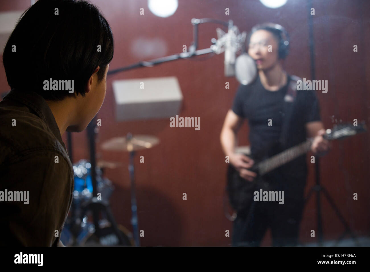 Young Chinese man singing with guitar in recording studio Stock Photo ...