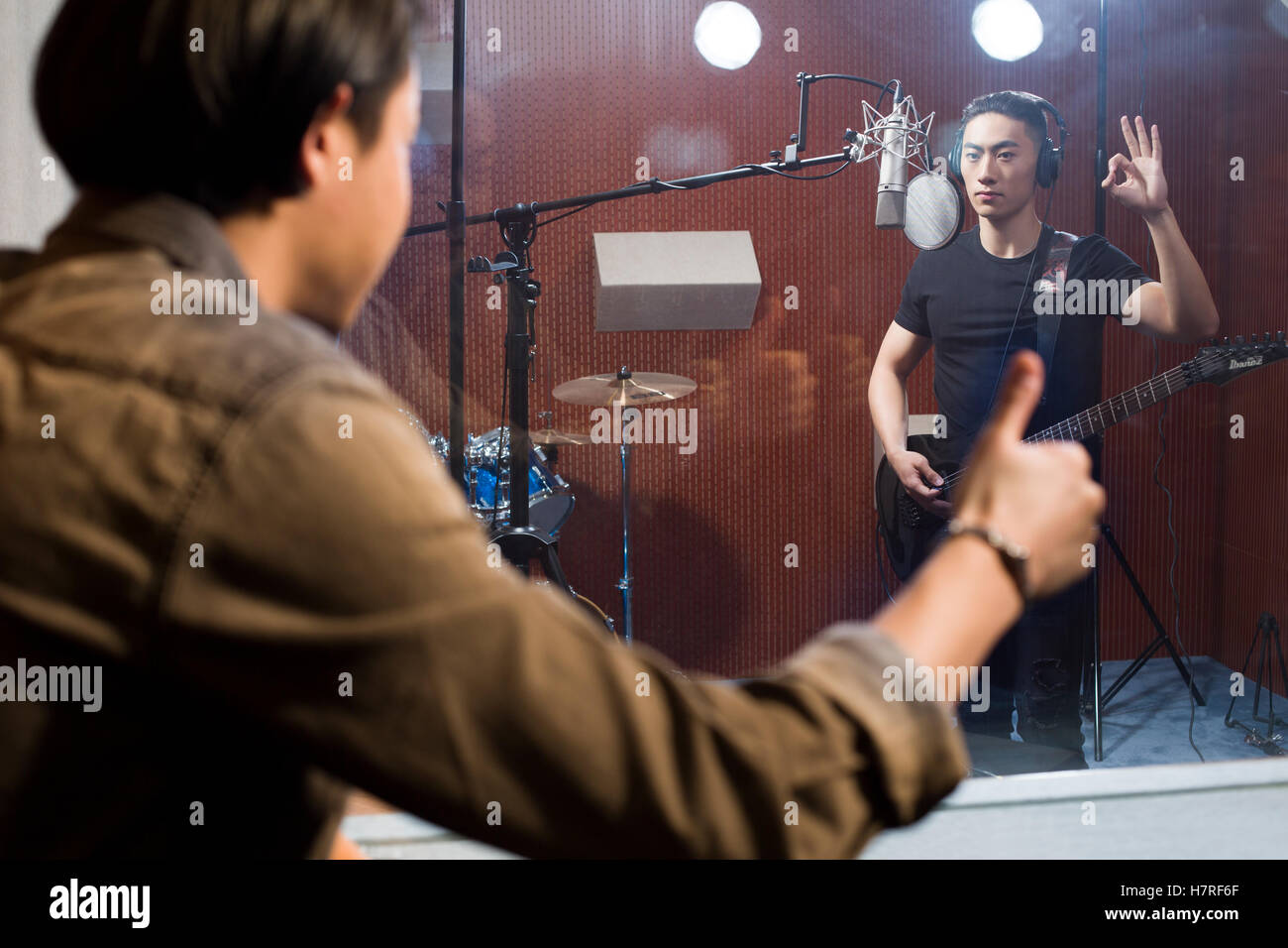 Young Chinese man singing with guitar in recording studio Stock Photo ...