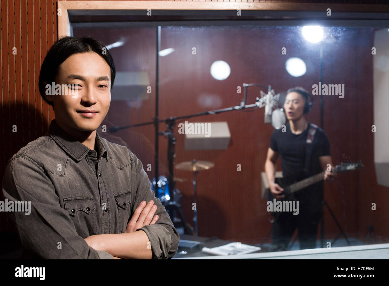 Young Chinese man singing with guitar in recording studio Stock Photo ...