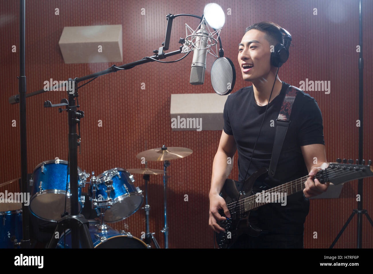Young Chinese man singing with guitar in recording studio Stock Photo - Alamy