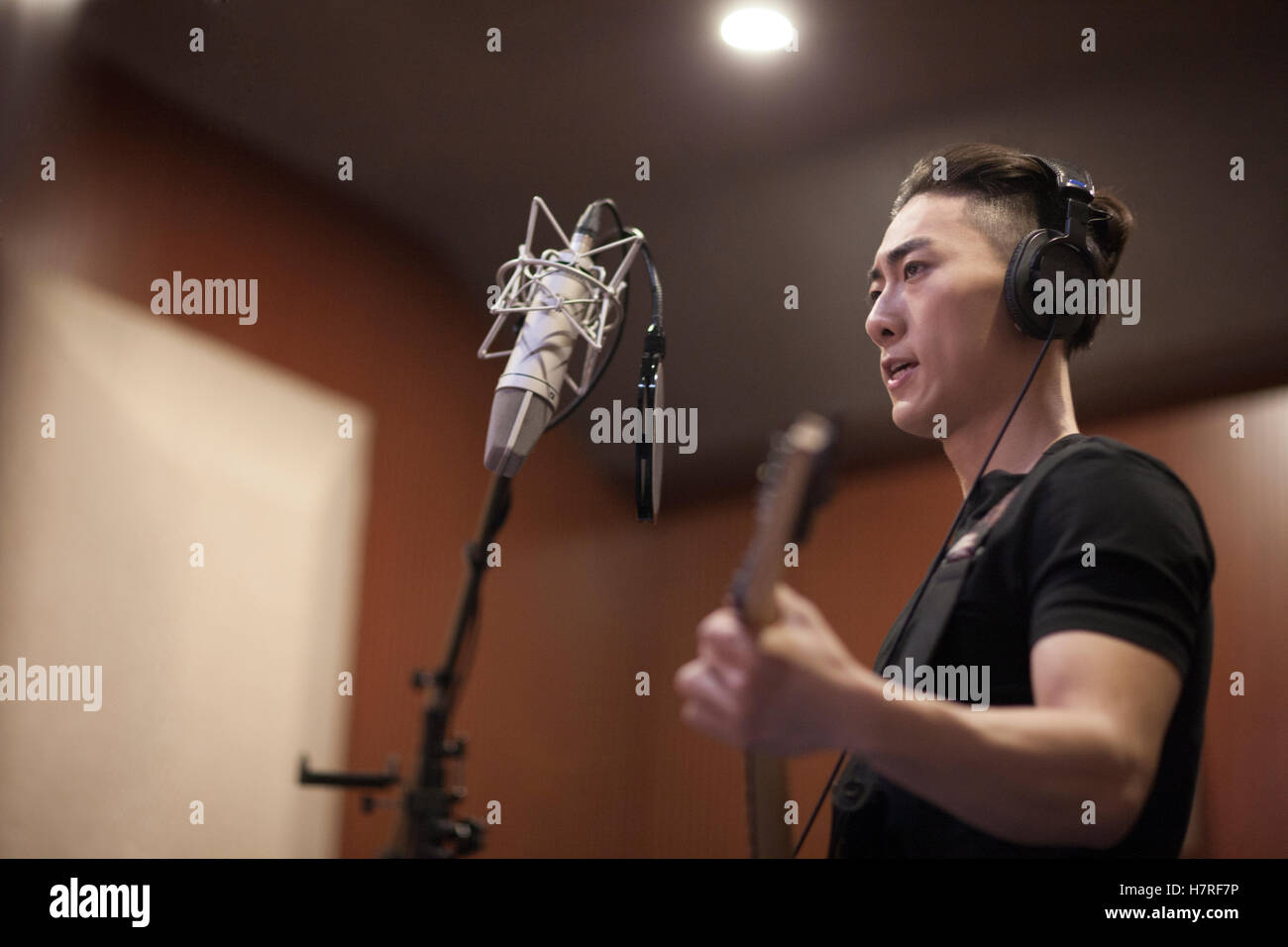Young Chinese man singing with guitar in recording studio Stock Photo - Alamy