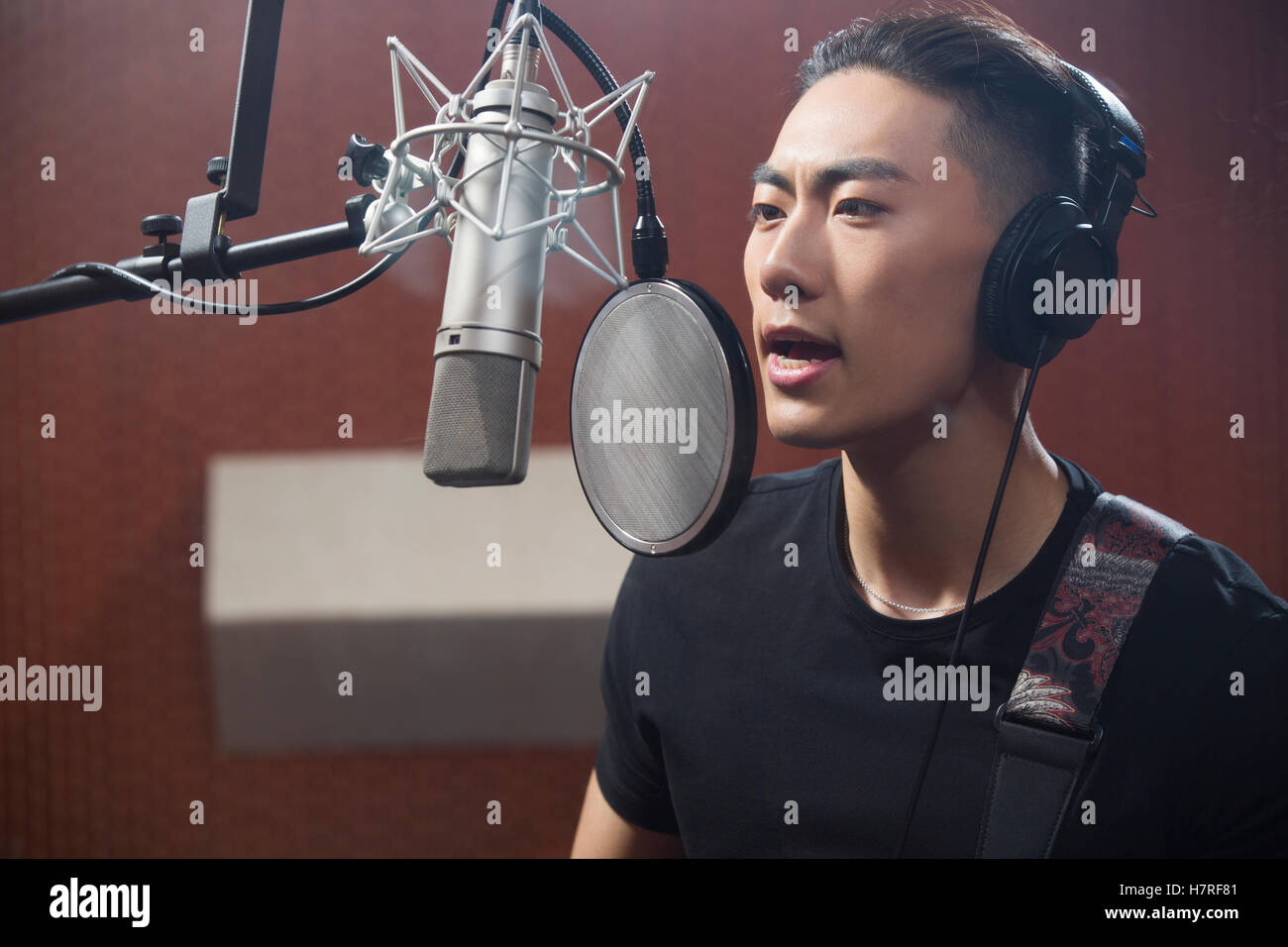 Young Chinese man singing in recording studio Stock Photo - Alamy