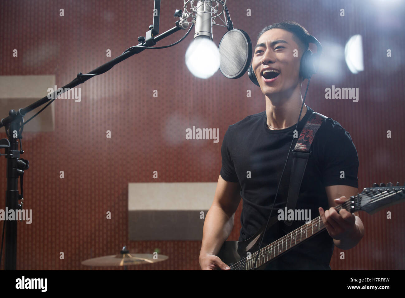 Young Chinese man singing with guitar in recording studio Stock Photo - Alamy
