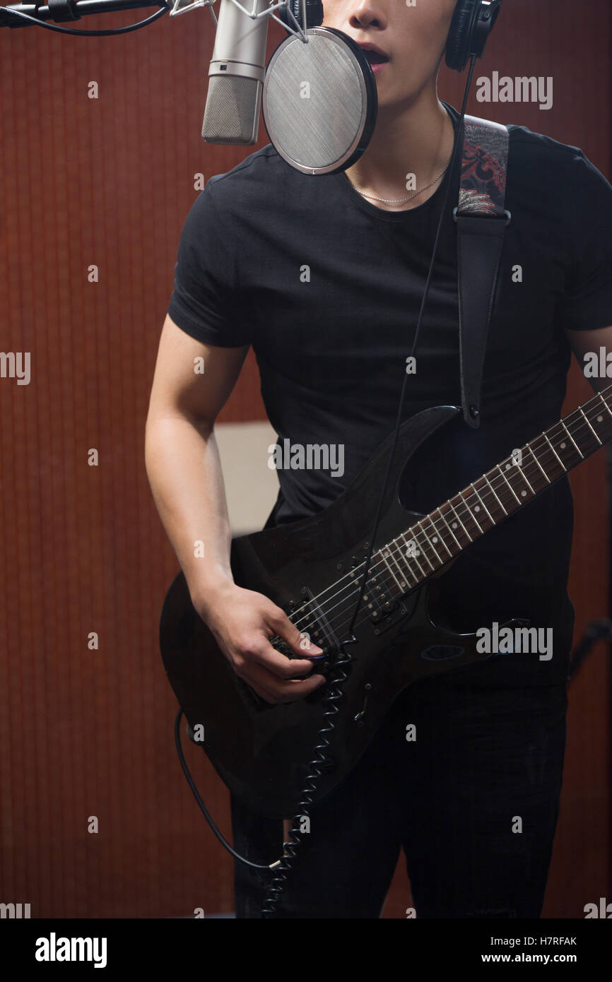 Young Chinese man singing with guitar in recording studio Stock Photo - Alamy