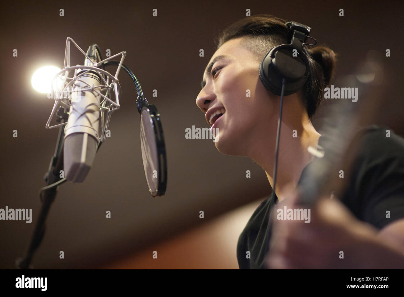 Young Chinese man singing with guitar in recording studio Stock Photo - Alamy
