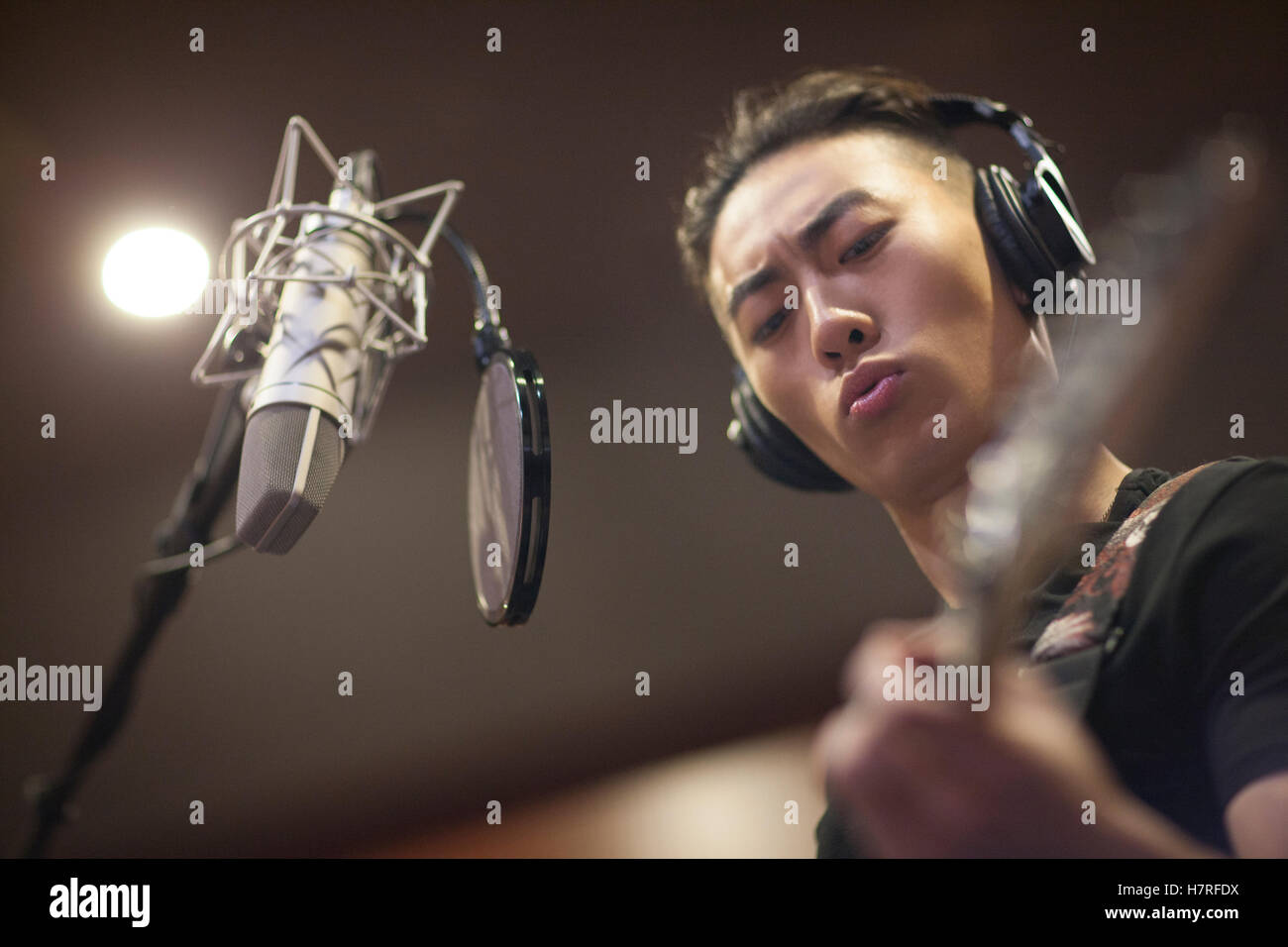 Young Chinese man singing with guitar in recording studio Stock Photo - Alamy