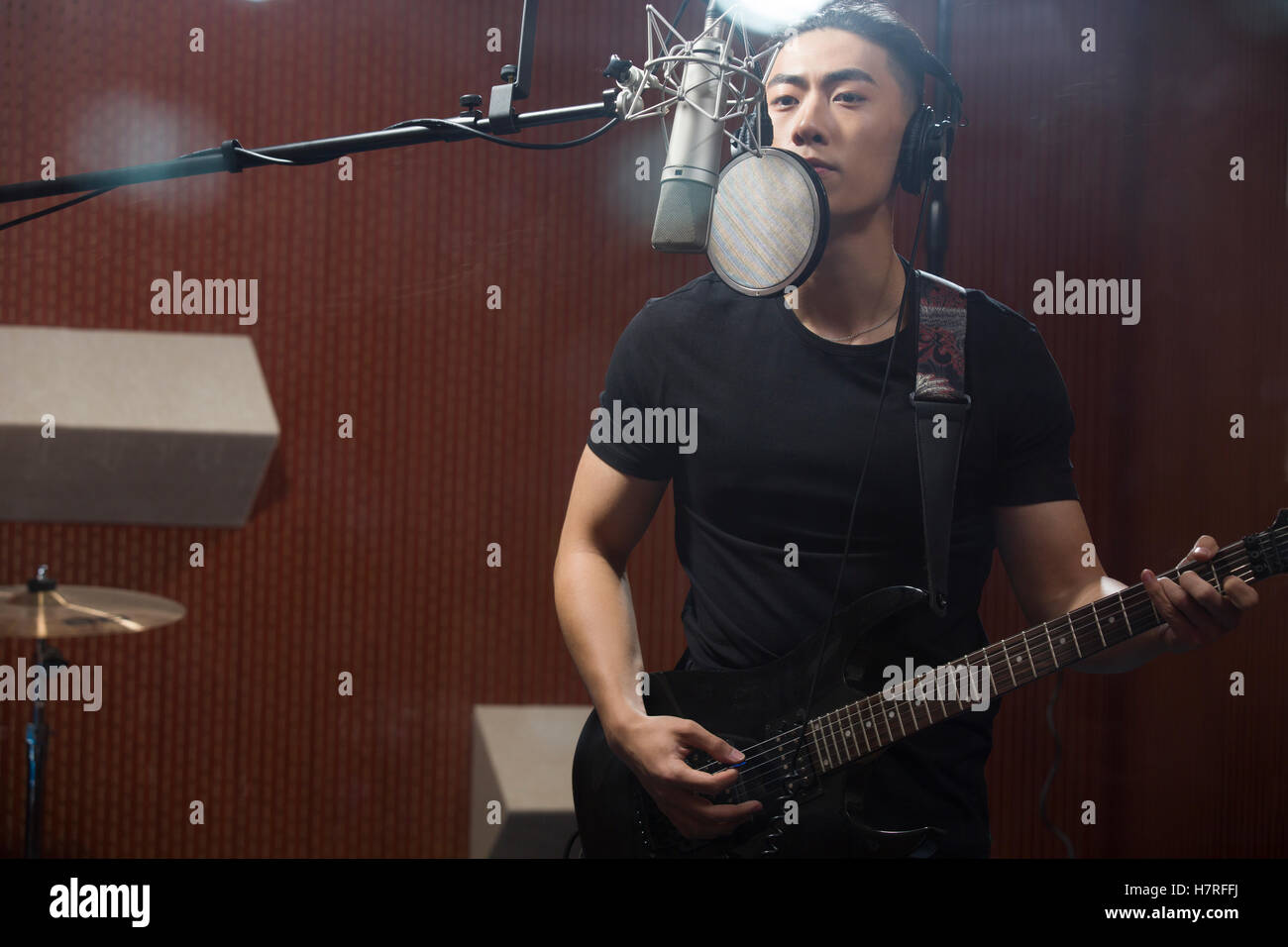 Young Chinese man singing with guitar in recording studio Stock Photo ...
