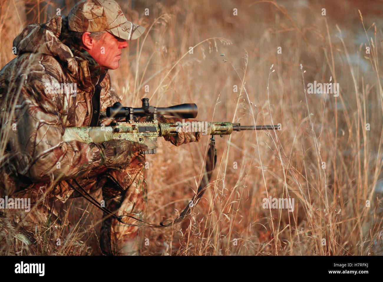 Predator Hunter Stalking In A Field With A Rifle Stock Photo - Alamy
