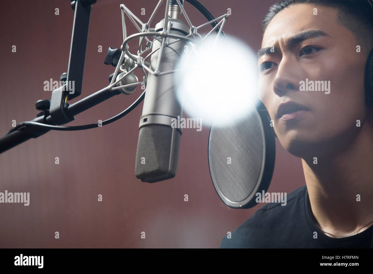 Young Chinese man singing in recording studio Stock Photo - Alamy