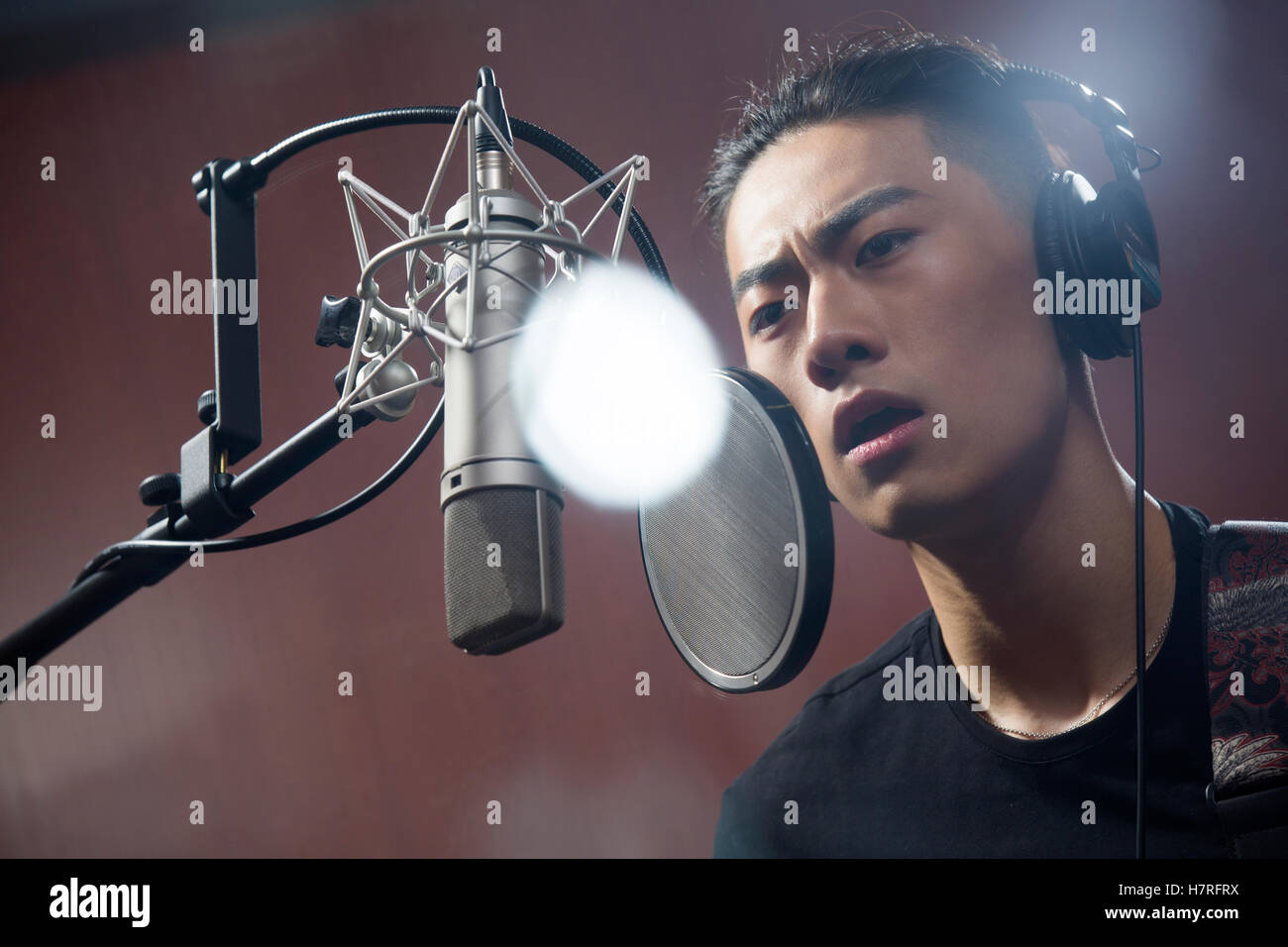 Young Chinese man singing in recording studio Stock Photo - Alamy