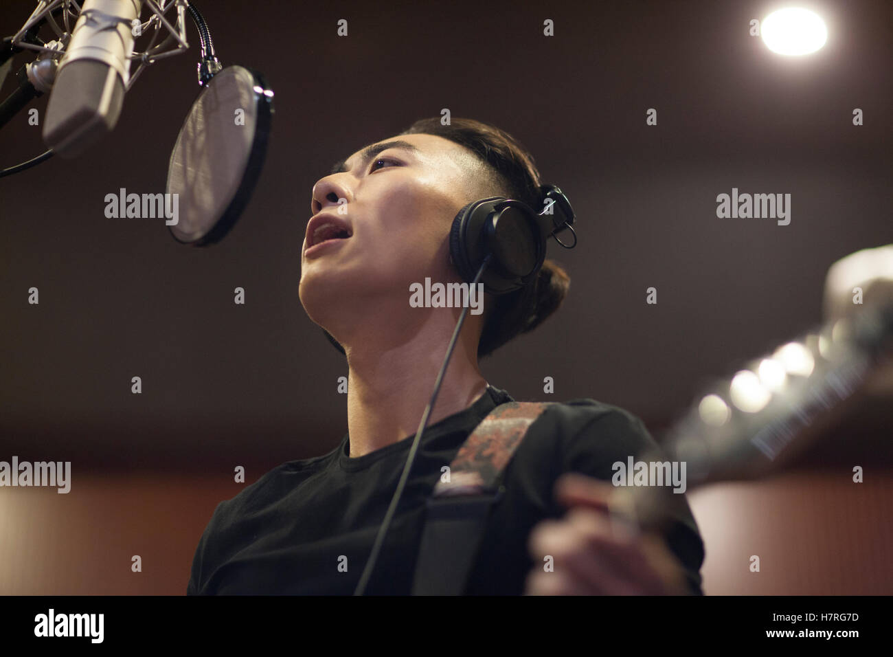 Young Chinese man singing with guitar in recording studio Stock Photo - Alamy