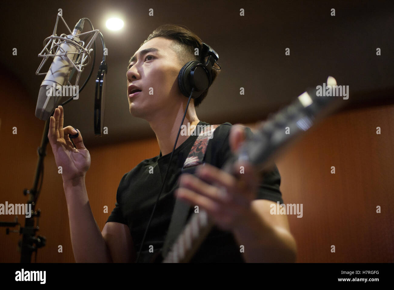 Young Chinese man singing with guitar in recording studio Stock Photo ...