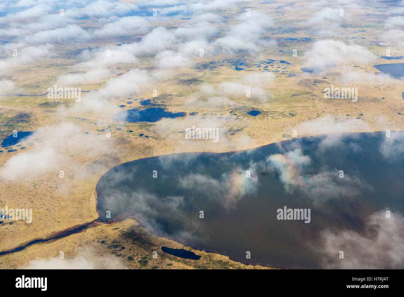 Aerial view of ponds dotting the tundra landscape, thin clouds above ...