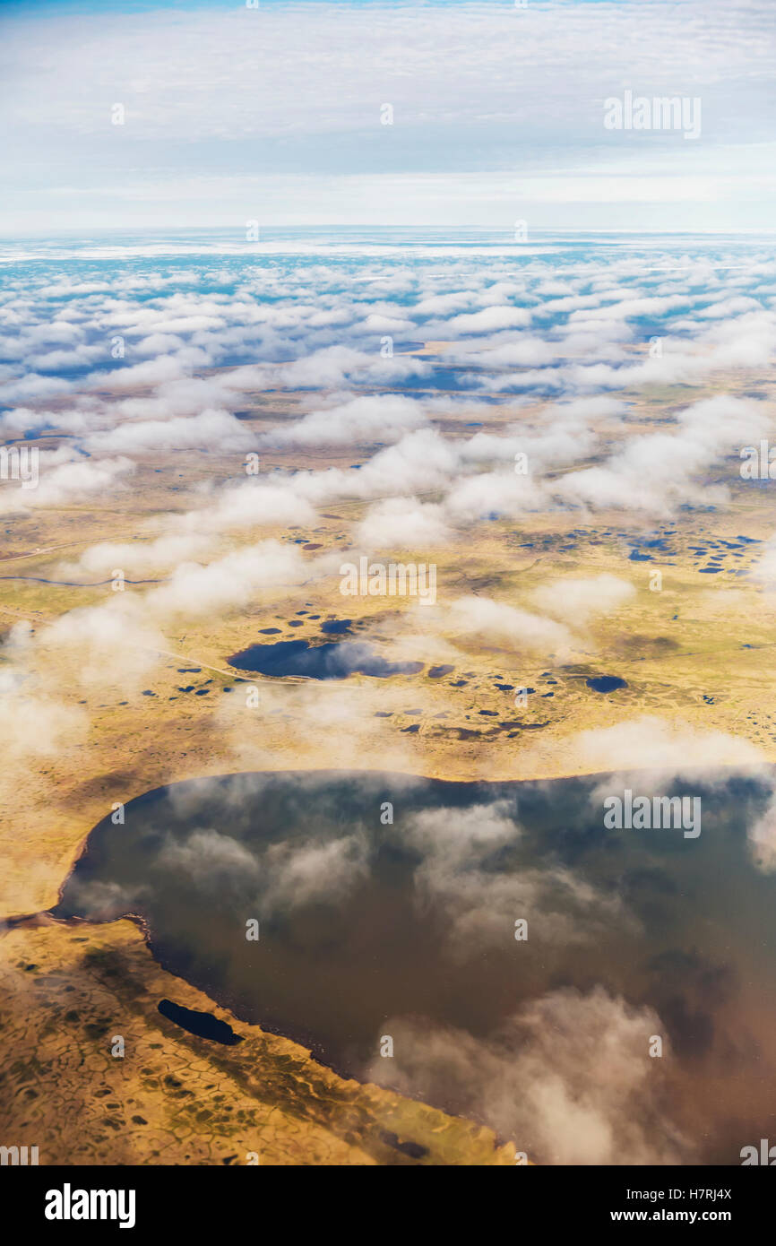 Aerial view of ponds dotting the tundra landscape, thin clouds above ...
