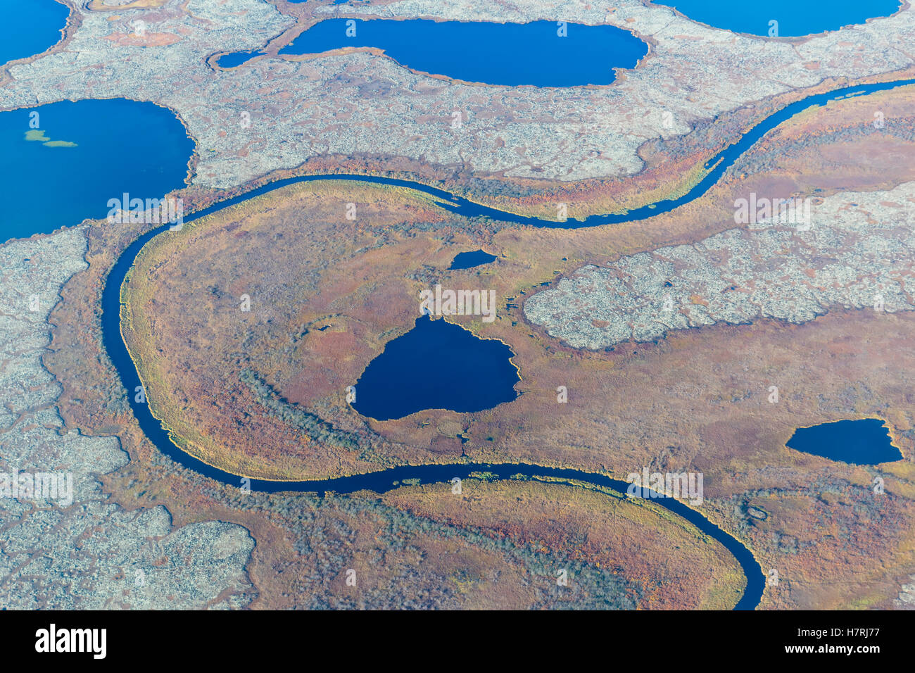 Aerial view of a stream that runs through a tundra landscape filled ...