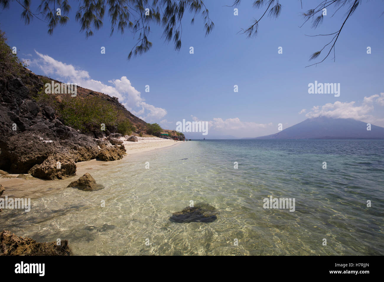 White sand beach with clear water and offshore volcano on the horizon ...