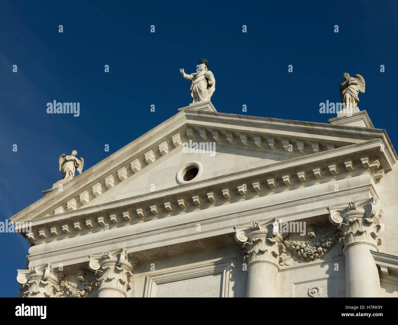 White facade of a building with statues of human figures along the roof ...