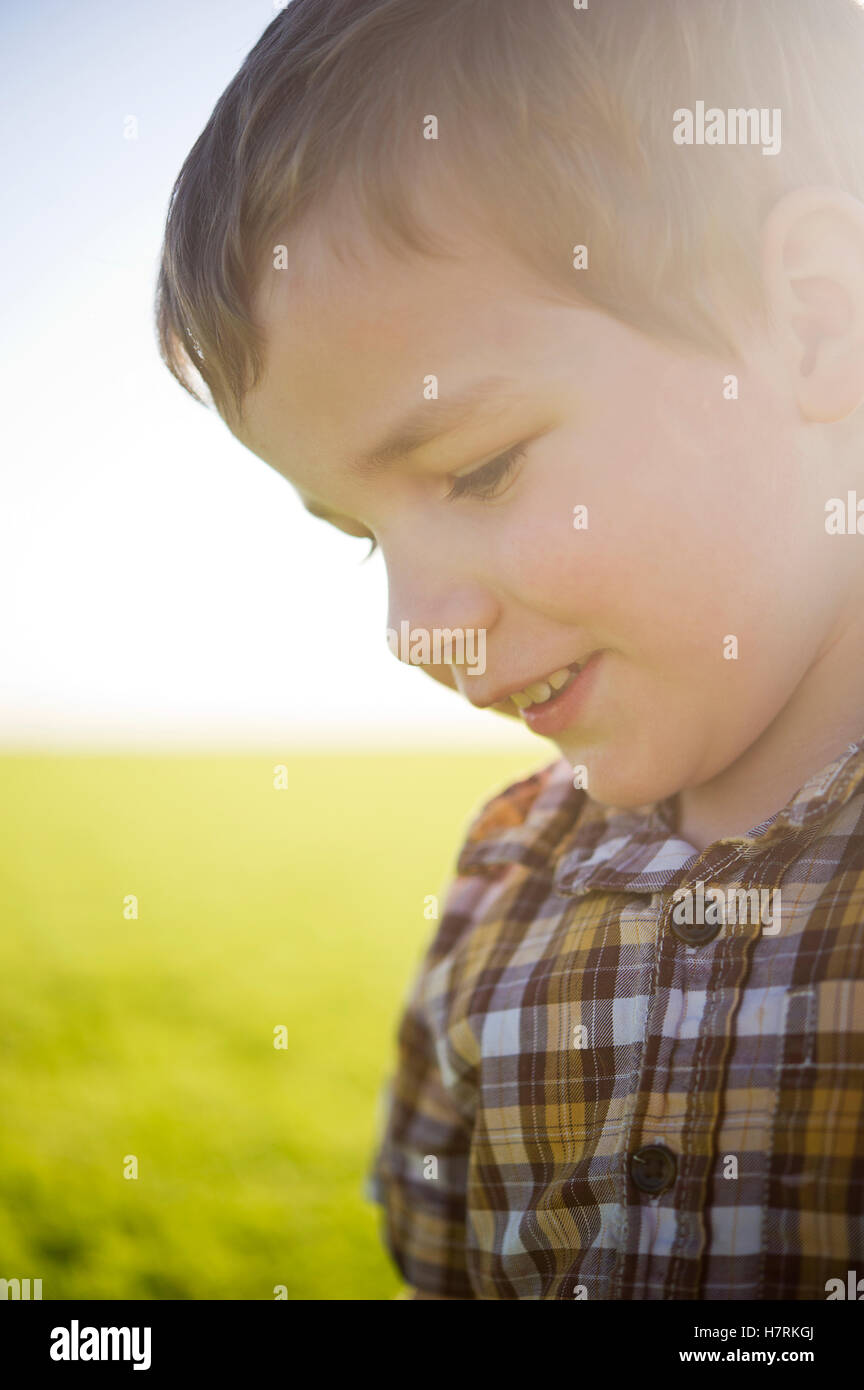 Young boy's profile with sunlight hitting his face in a farm field ...