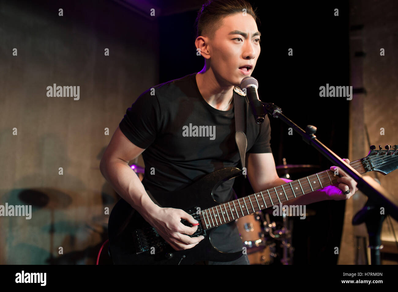 Young Chinese man singing with guitar on stage Stock Photo - Alamy