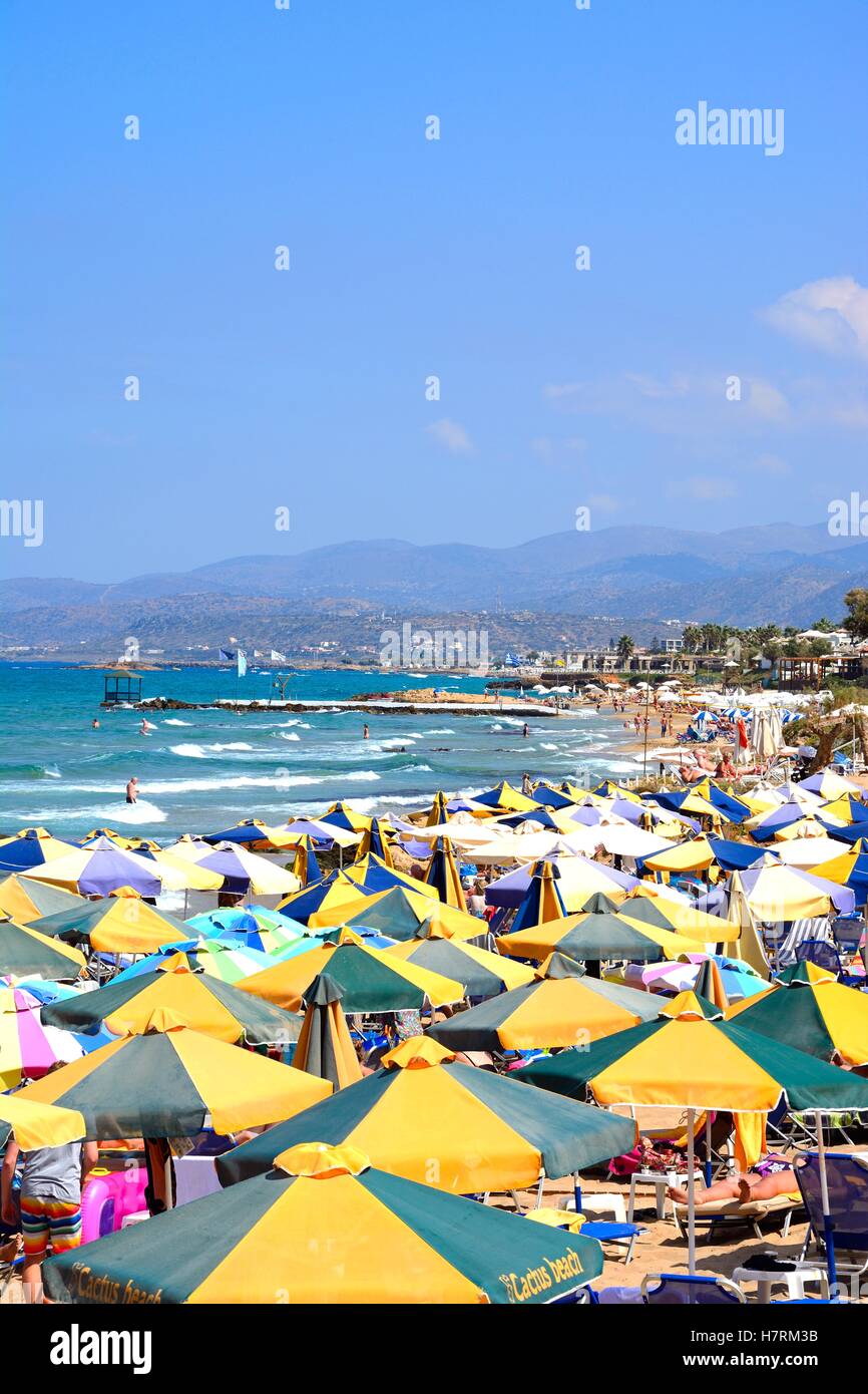 Tourists relaxing on the beach with views along the coastline, Stalida ...