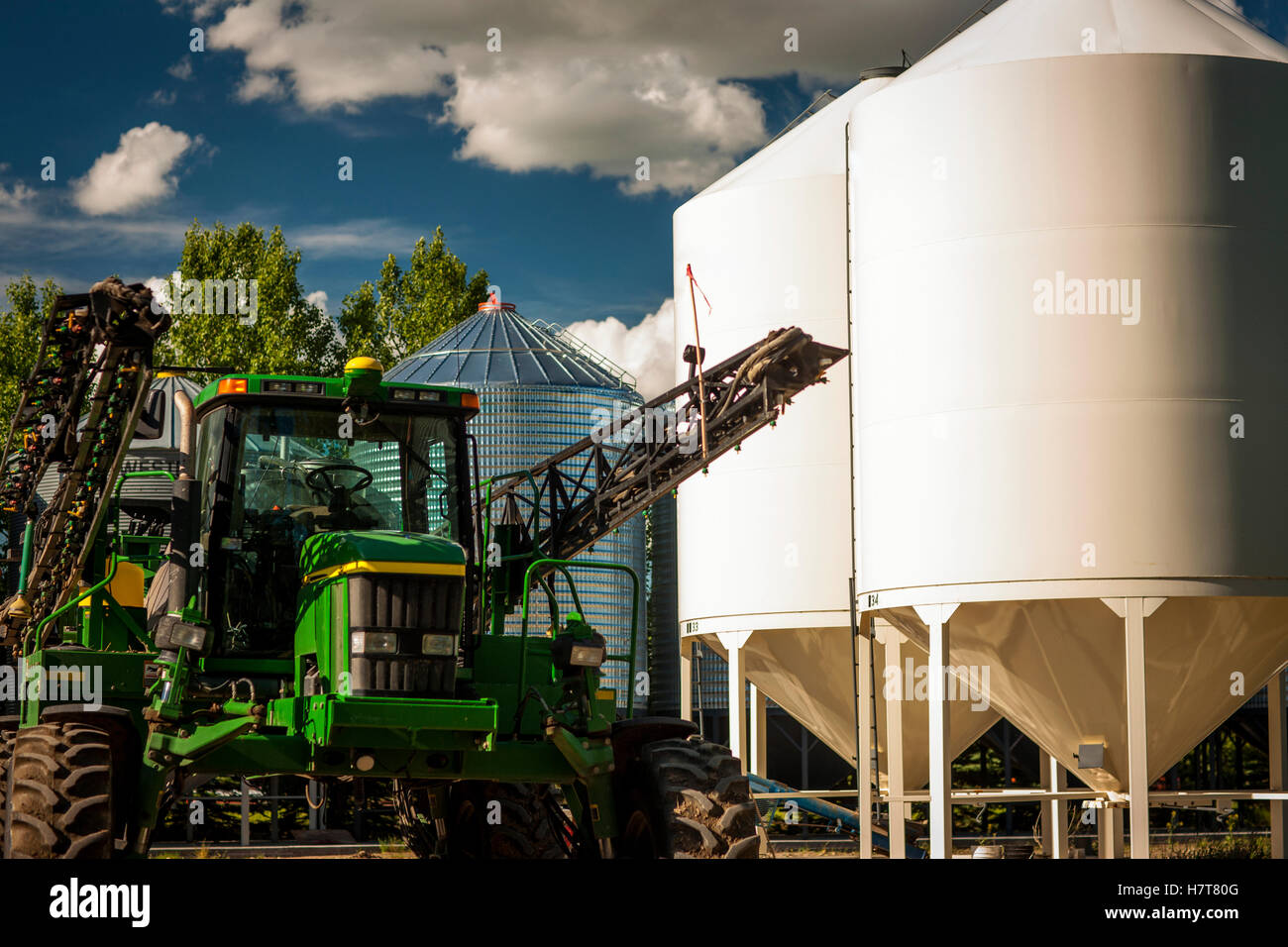 Farm equipment and grain storage bins on a farm; Saskatchewan, Canada ...