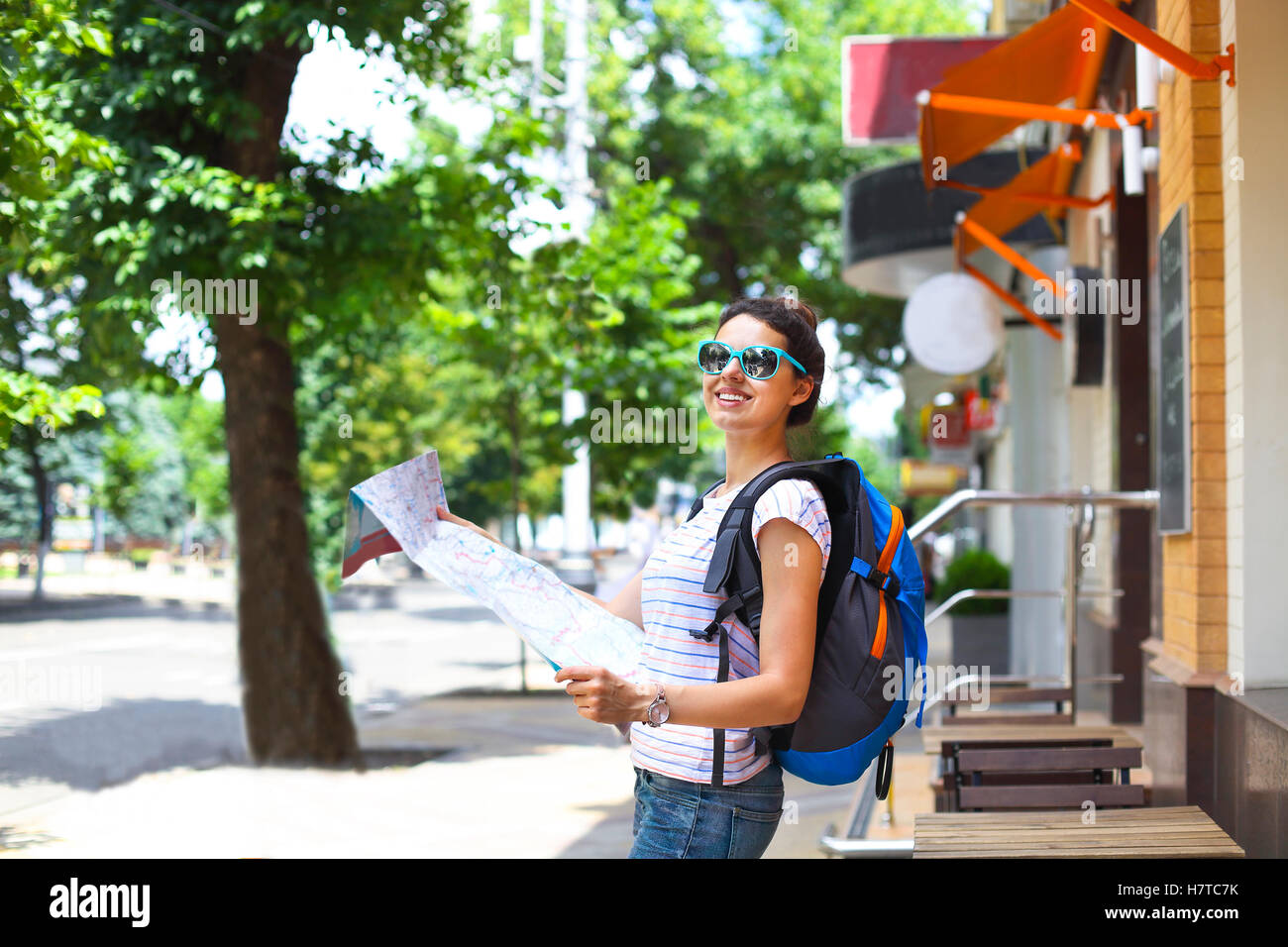 Cheerful woman searching direction on location map while traveling ...