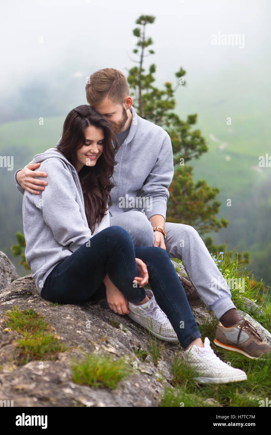 Young loving couple relaxing and hugging, she is smiling and leaning on ...