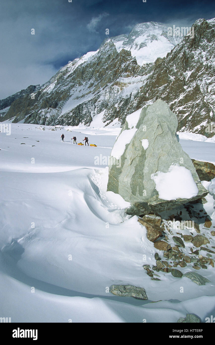Three climbers pulling sleds under Broad Peak, Godwin Austen Glacier ...