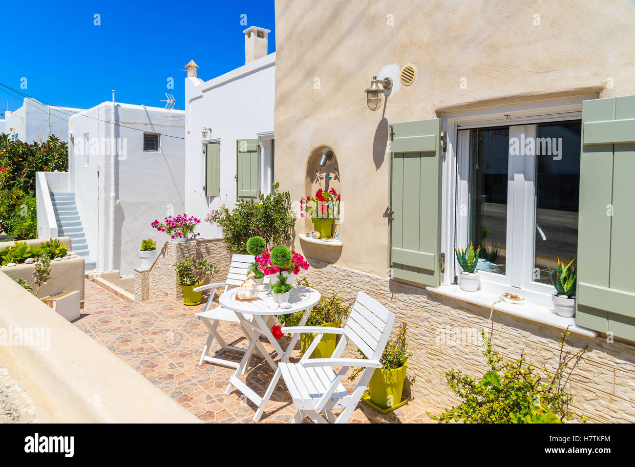 White chairs with tables on terrace of typical Greek house on street in ...