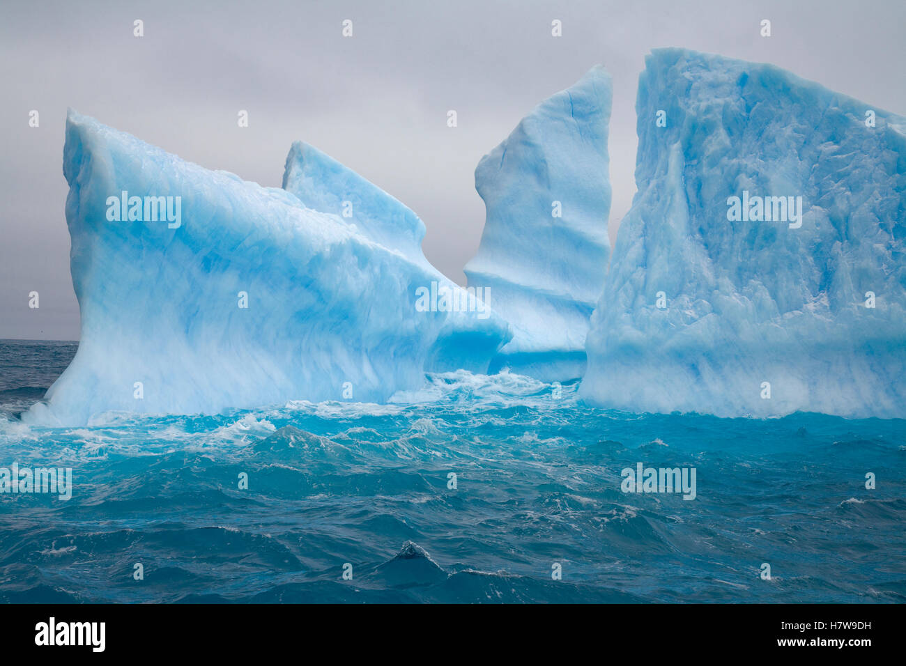 Blue iceberg with tall towers sculpted by waves and melting action ...