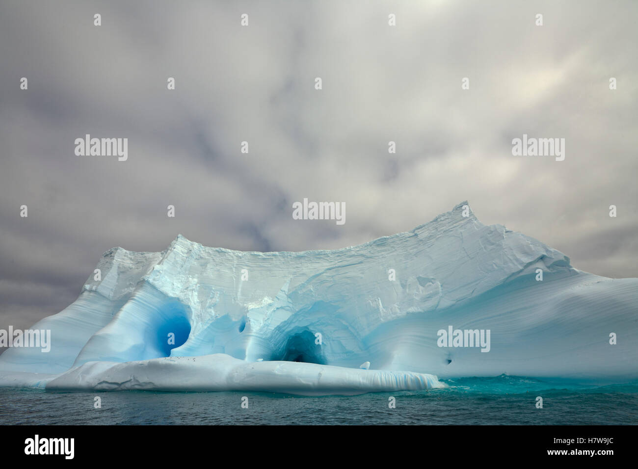 Blue iceberg dramatically sculpted by waves and melting action ...