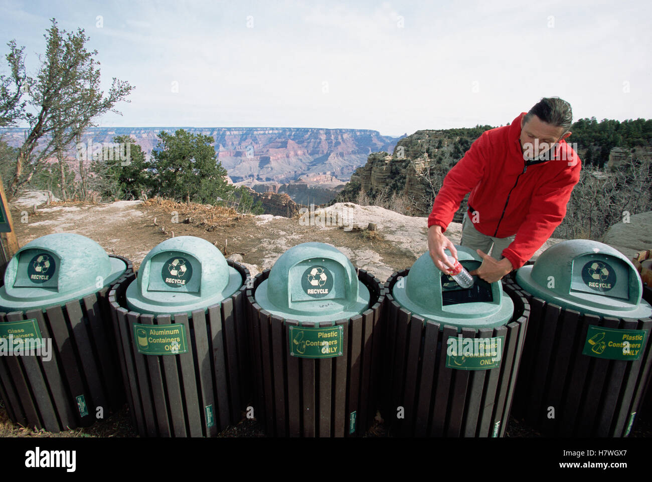 Tourist depositing plastic bottle into recycling garbage cans in ...