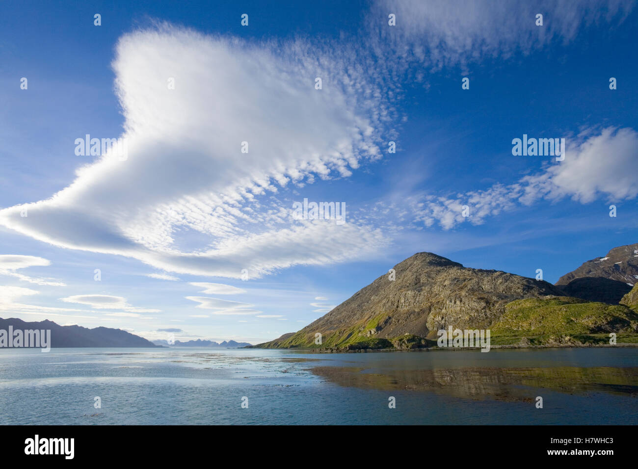 White dramatic lenticular clouds over coastal mountains, fall evening ...