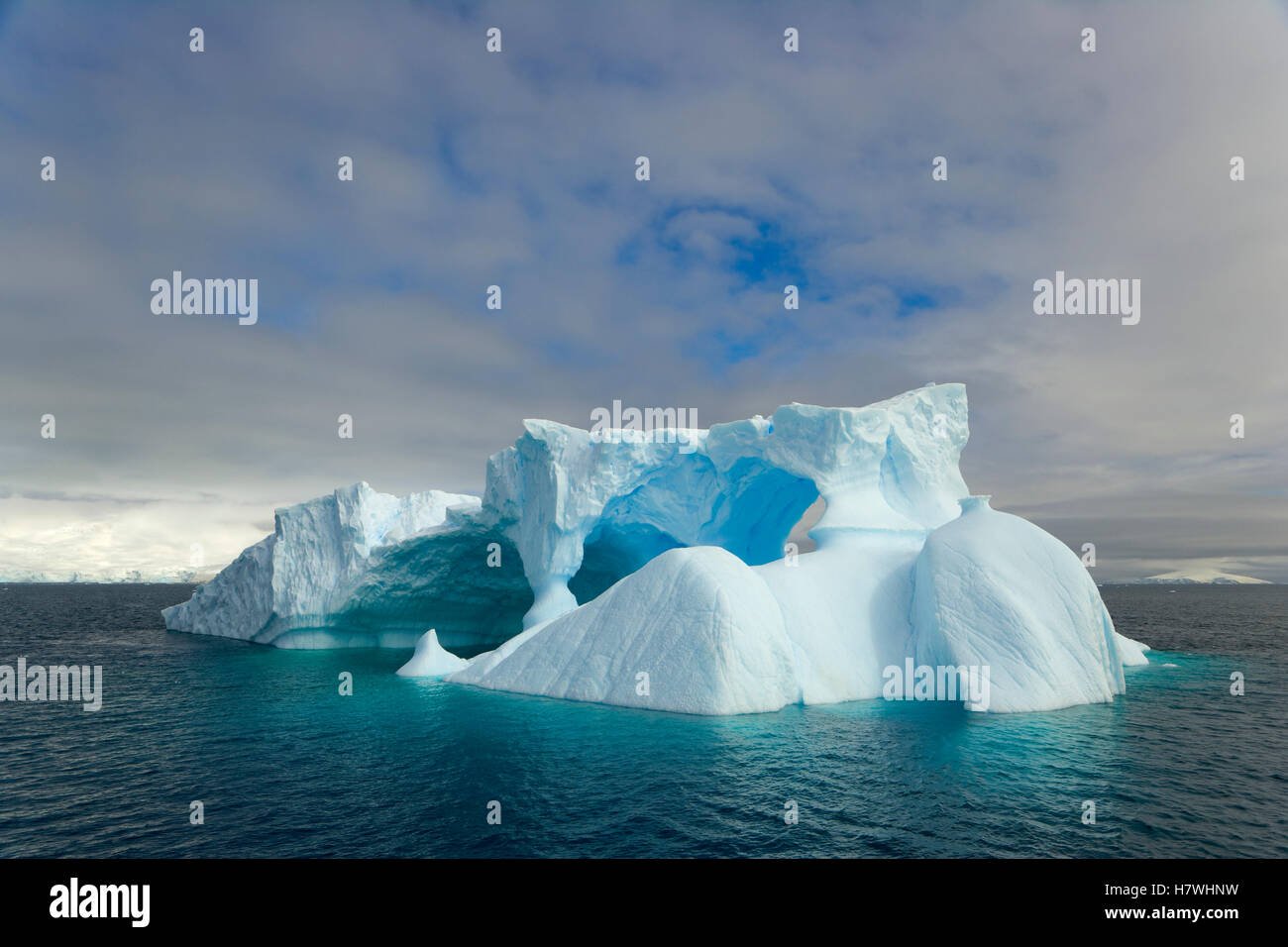 Iceberg with arches and turrets sculpted by waves and melting of ice ...